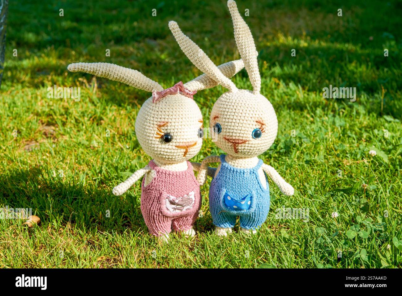 Two toy rabbits on the green grass on a summer day. Background for an ...