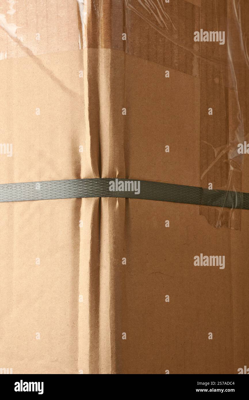 large cardboard box secured with wide dark green plastic strap, wrapped ...