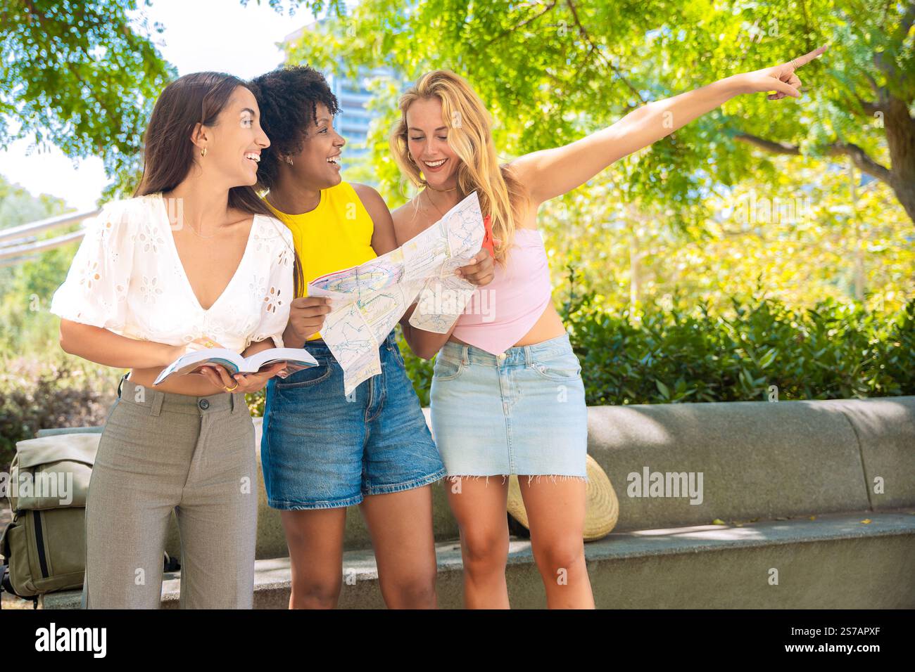 Three young women exploring the city with maps and a travel guide ...