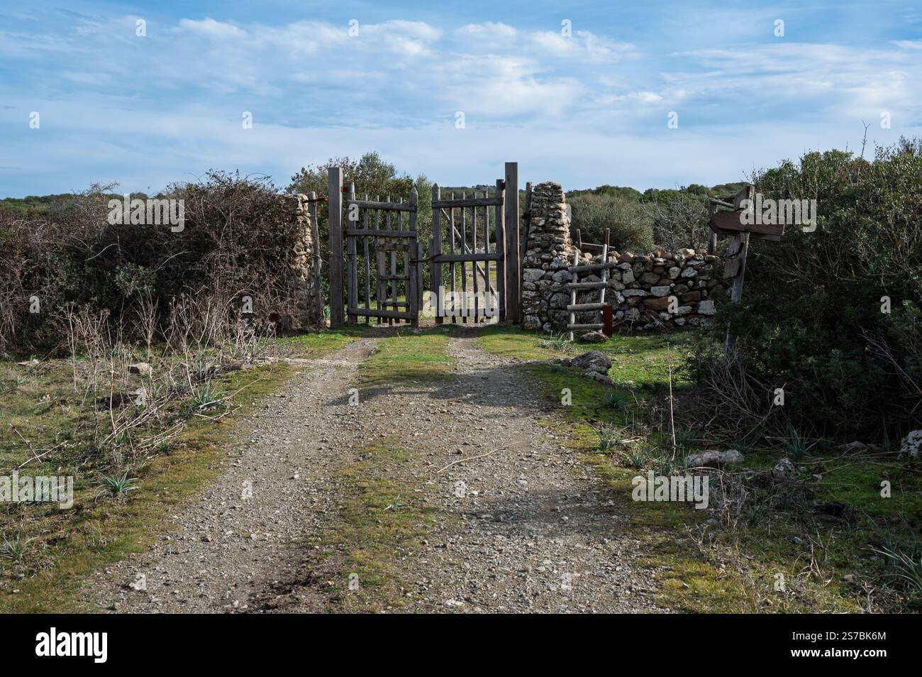 A rustic wooden gate with dry stone walls, located in a rural ...