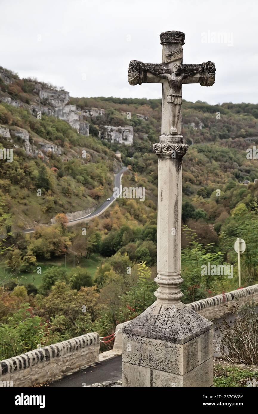 A stone cross stands at the edge of a cliff, overlooking the lush ...