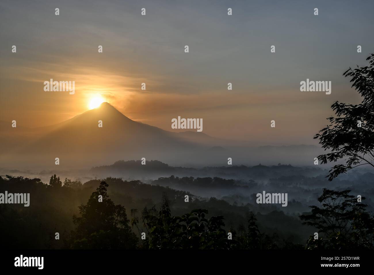 Sunrise over Borobudur in the morning mist and smoking Merapi vulcano ...