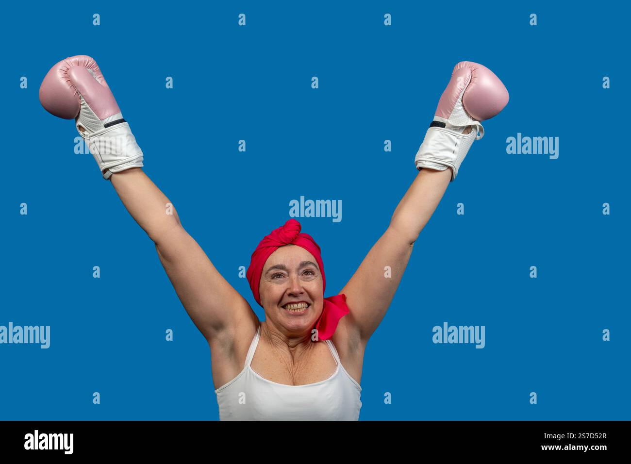 Smiling mature woman wearing pink boxing gloves raising her arms in ...