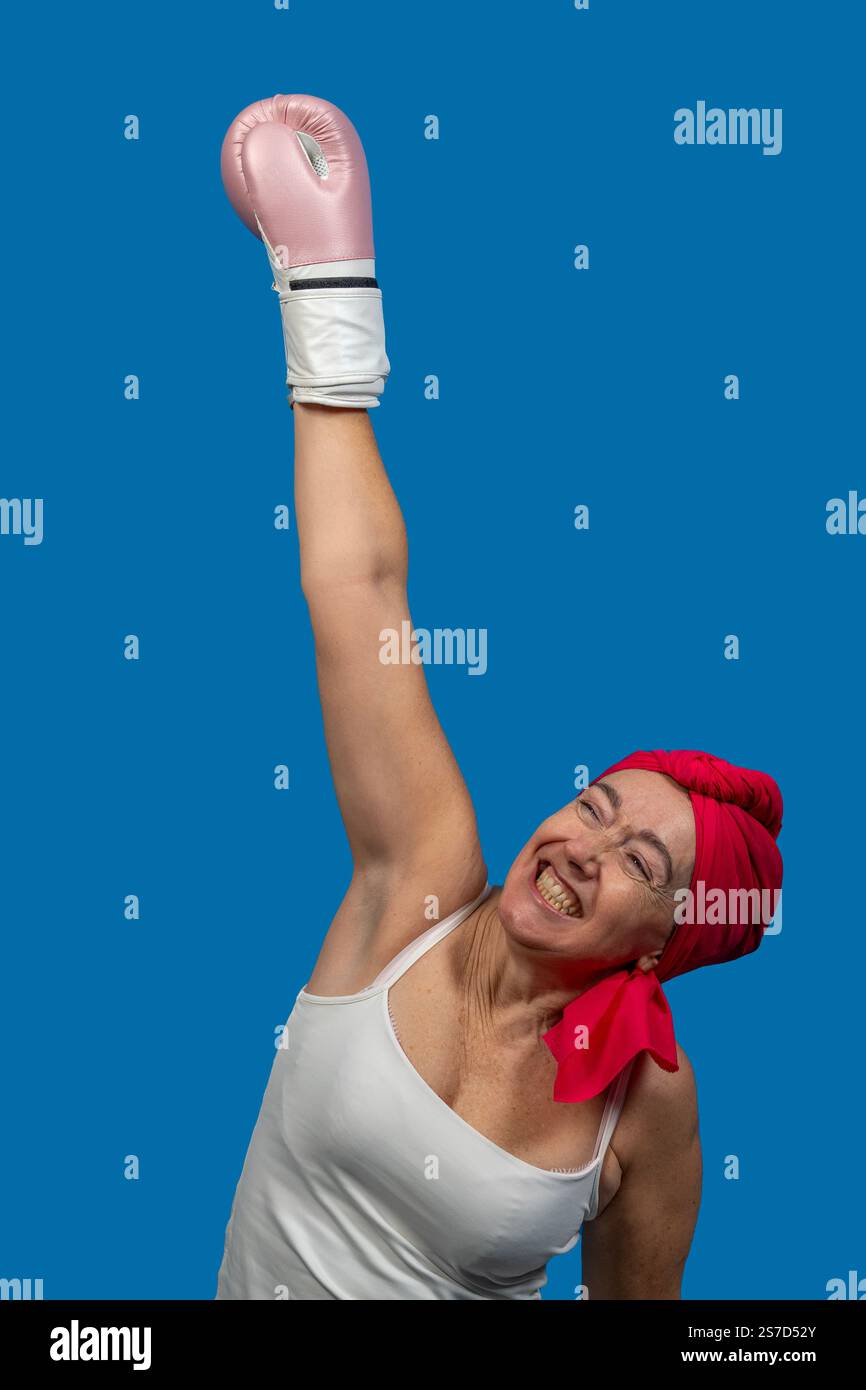Happy elderly woman wearing pink boxing glove raising arm in ...