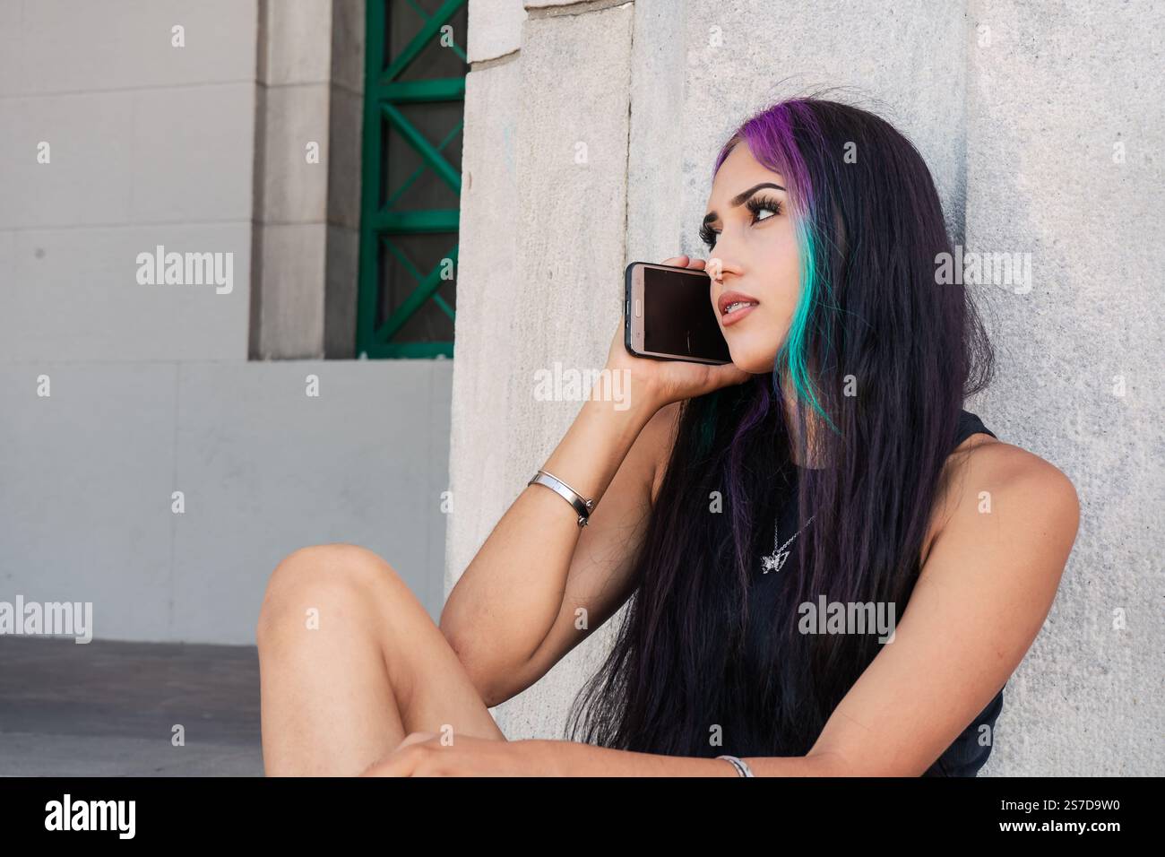 Young woman sitting talking on her cell phone on a staircase landing ...