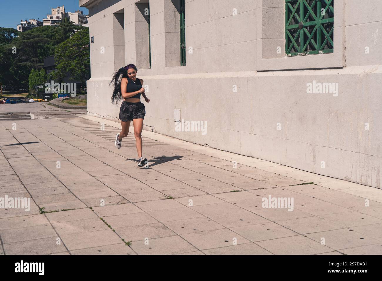 Young woman running on the sidewalk next to the building Stock Photo ...