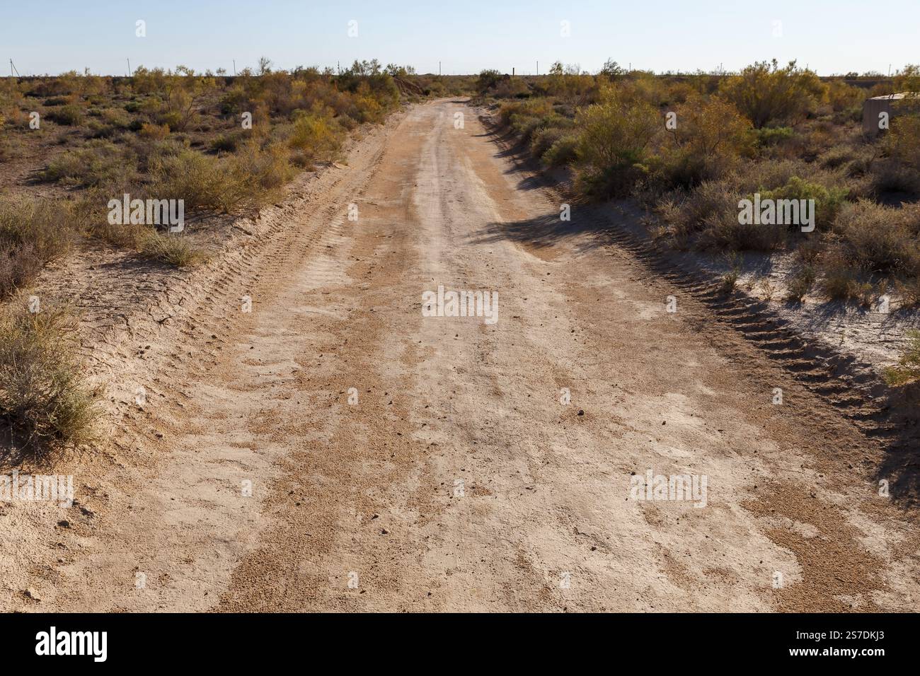 A dusty dirt road stretches through the dry landscape of Karakalpakstan ...