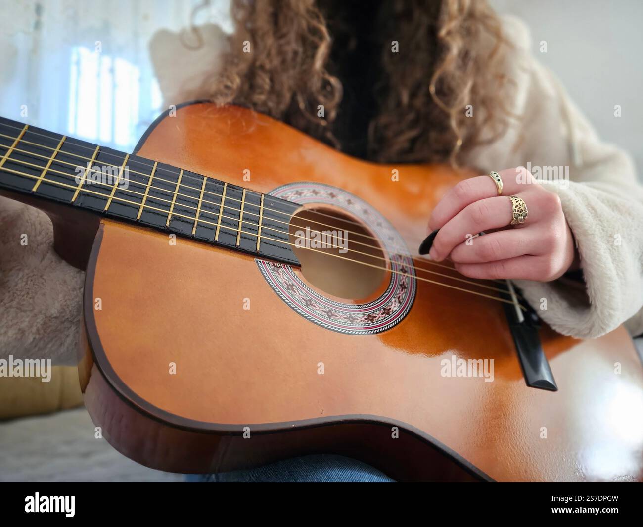 The young, curly-haired girl plays her acoustic guitar with passion and ...