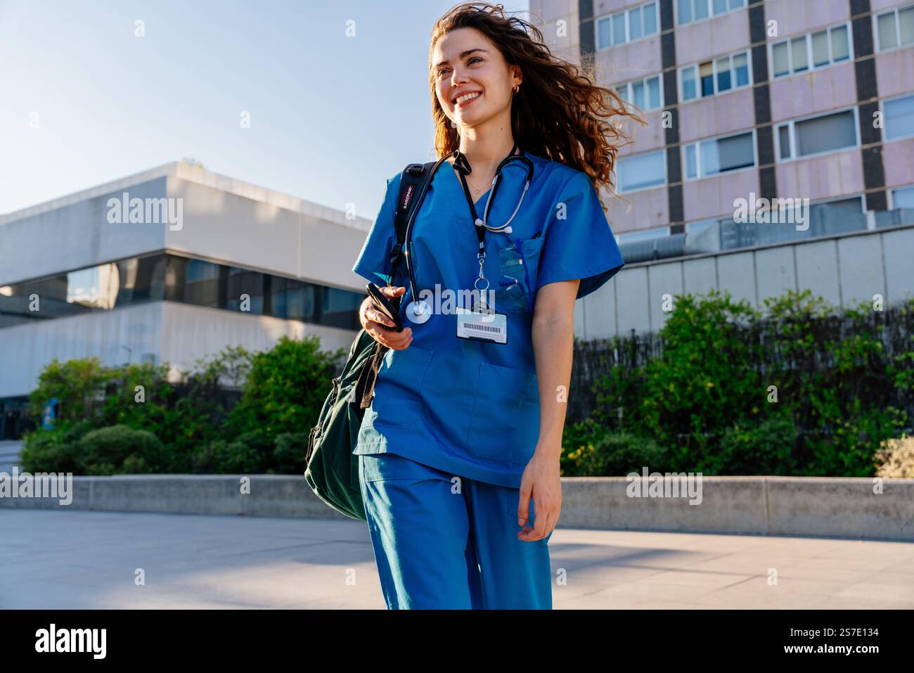 Beautiful young nurse wearing hospital blue uniform strolling in the ...
