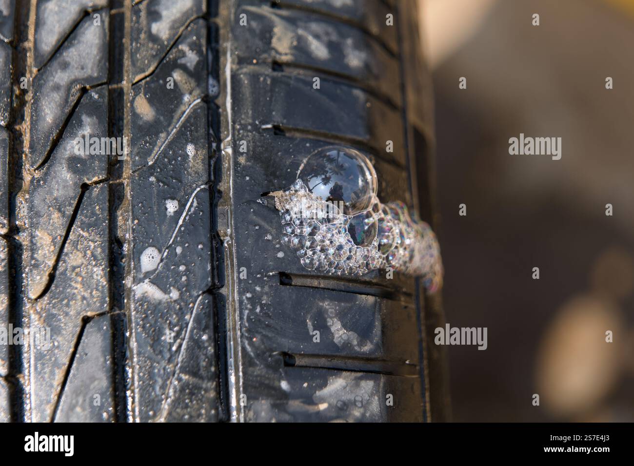 This image captures a close-up view of a car tire with soap bubbles on ...