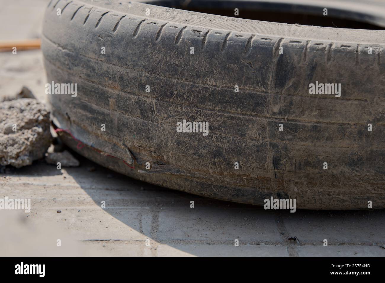 This image captures a close-up view of a worn and damaged tire lying on ...