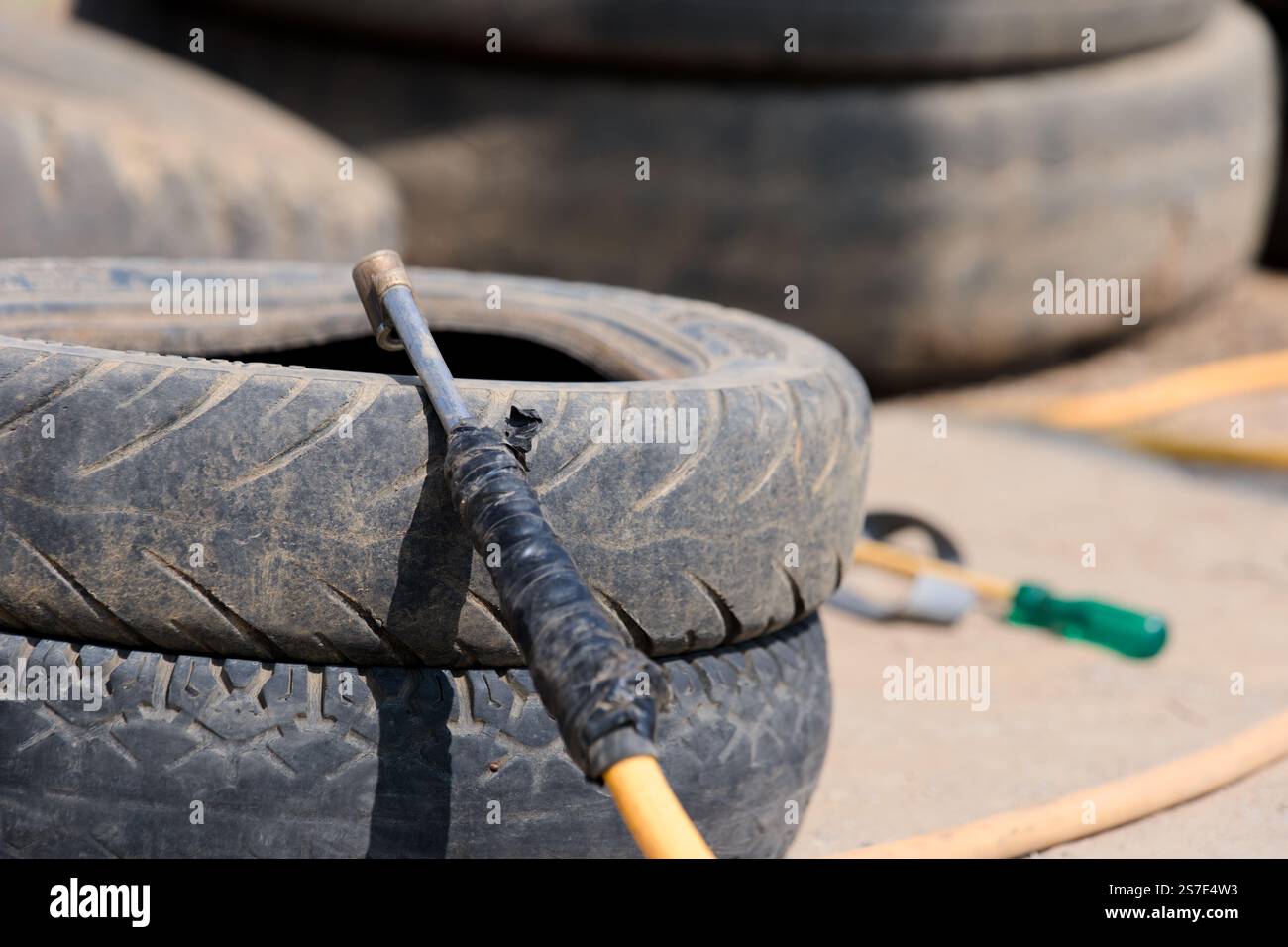 This image shows a close-up view of a stack of used tires. One of the ...