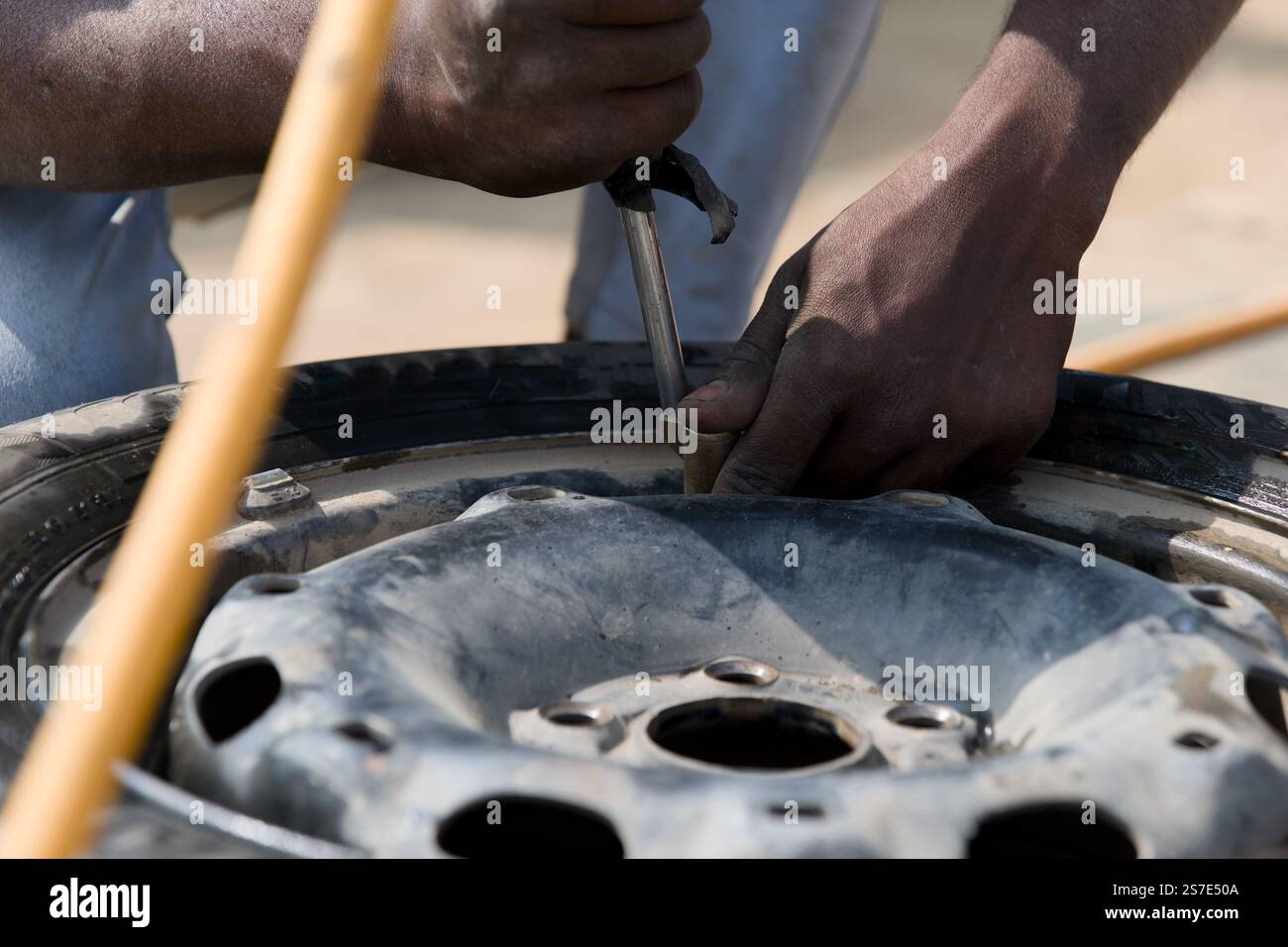 The tire is visibly worn and dirty, and the wheel rim has several holes ...