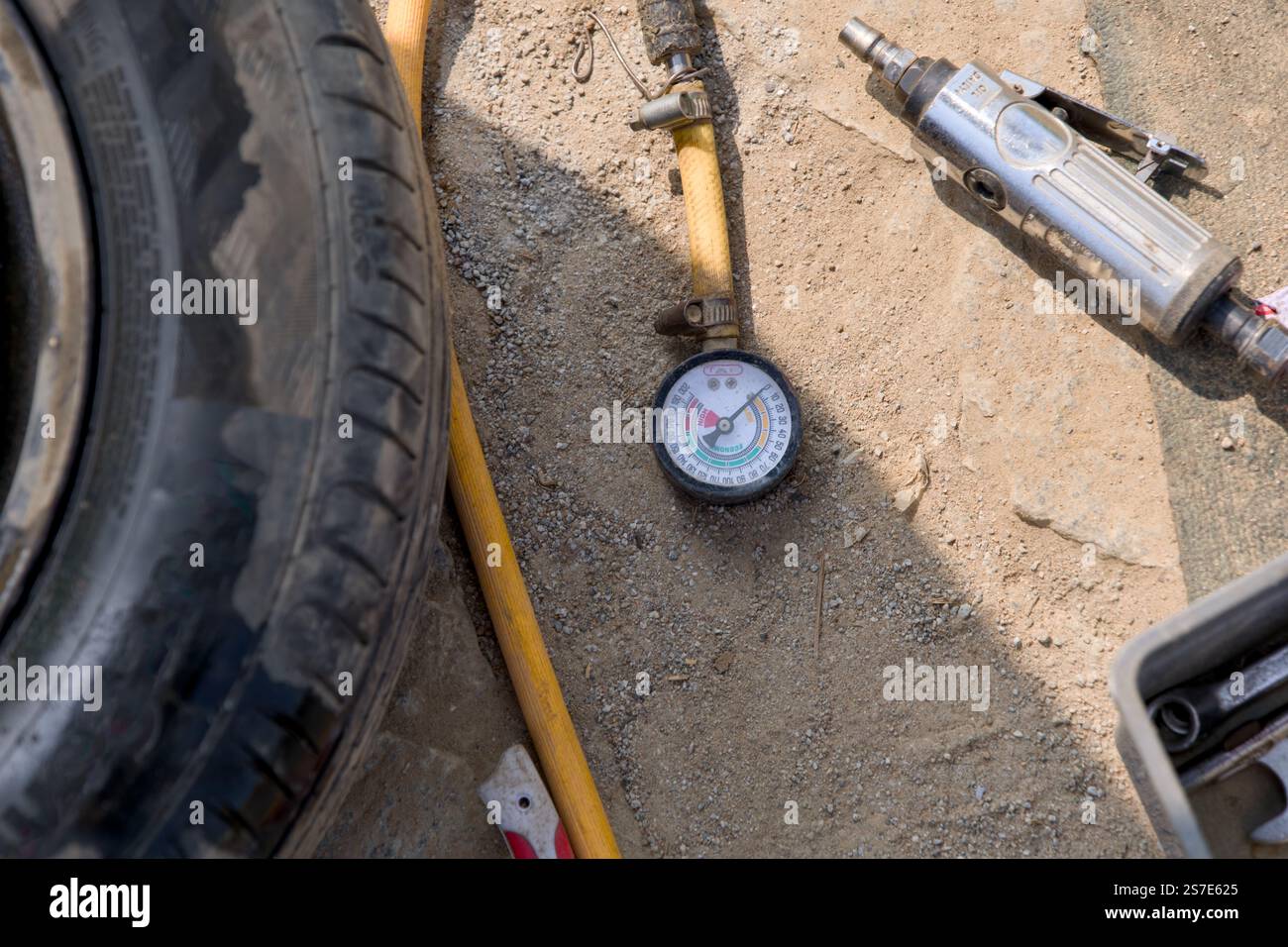 This image shows a close-up view of a tire maintenance setup on a sandy ...