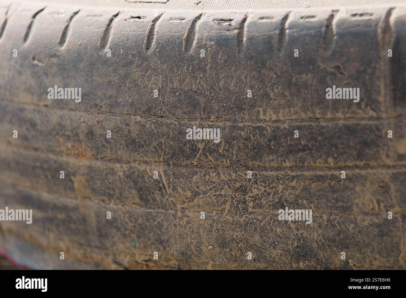 This image features a close-up view of a worn-out tire on a dirty ...