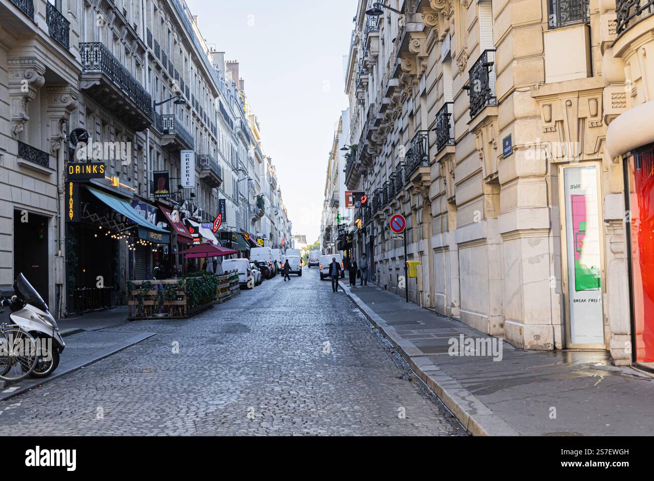 A narrow street in Paris with beautiful buildings and parked cars ...