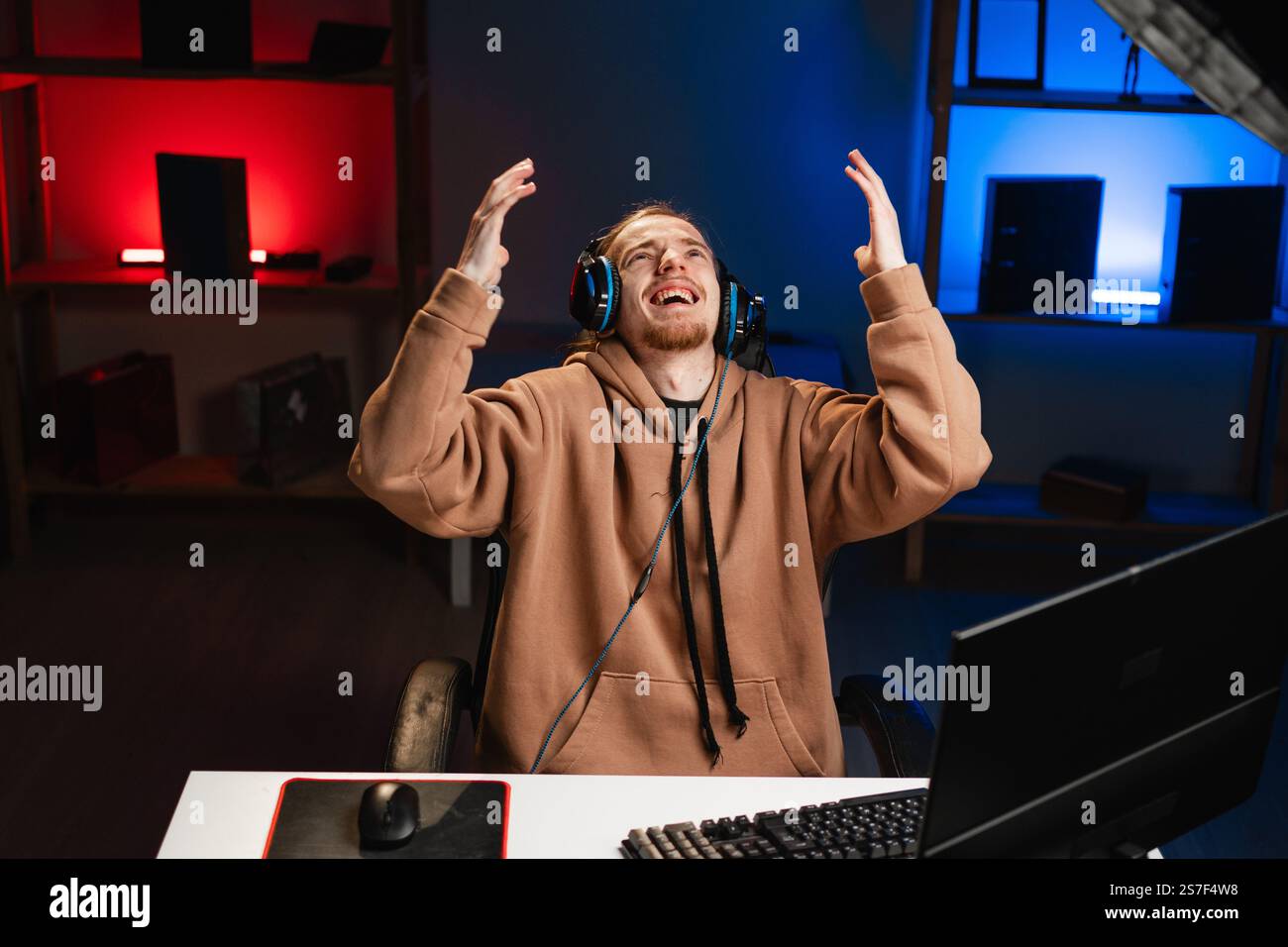 Happy smiling male gamer in headphones raised arms up play video game ...