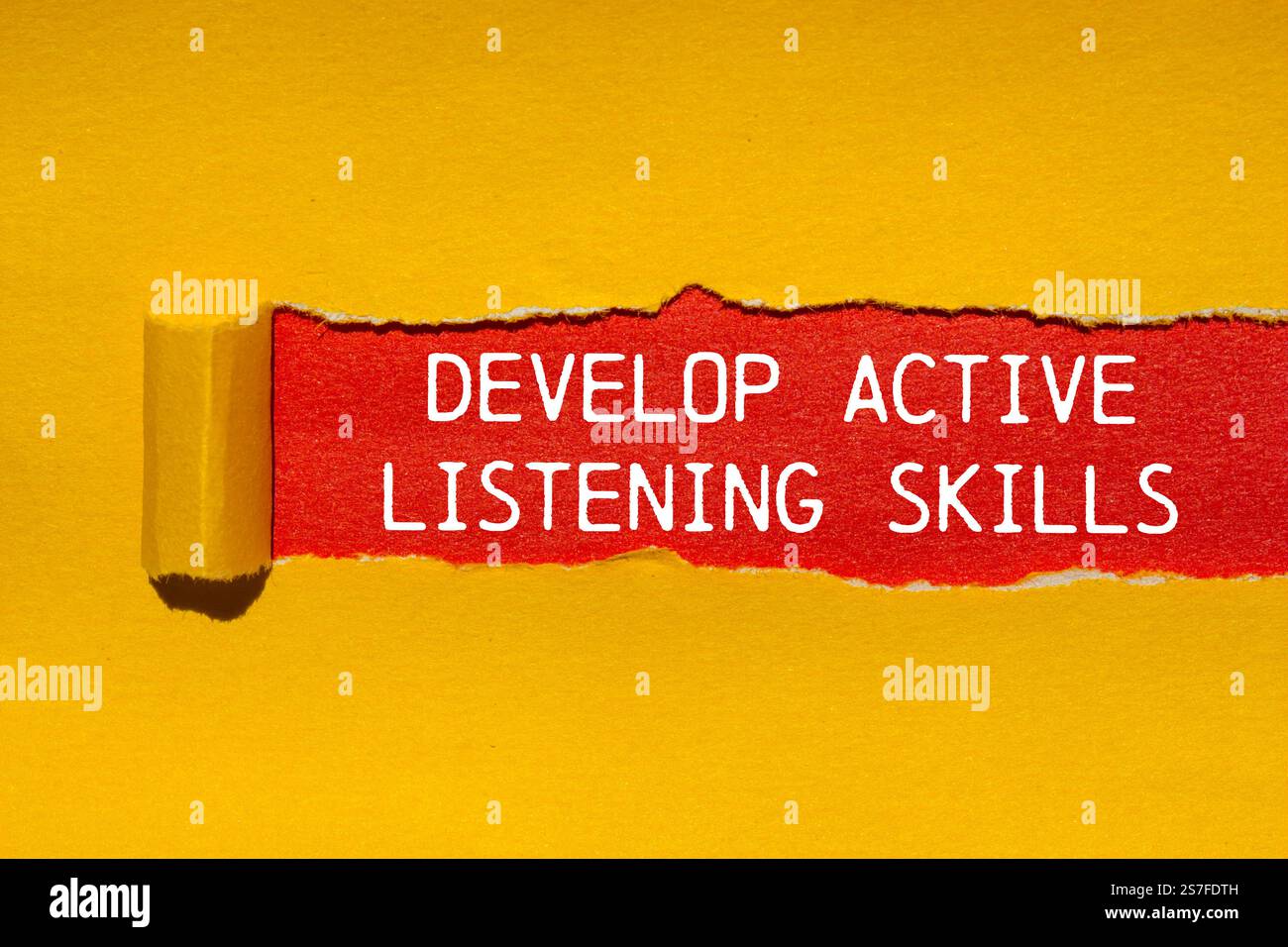 Develop active listening skills message written on ripped torn yellow paper with red background ...