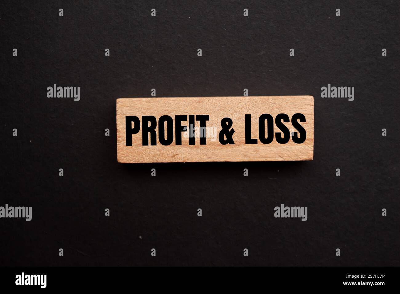 Profit and loss message written on wooden block with black background ...