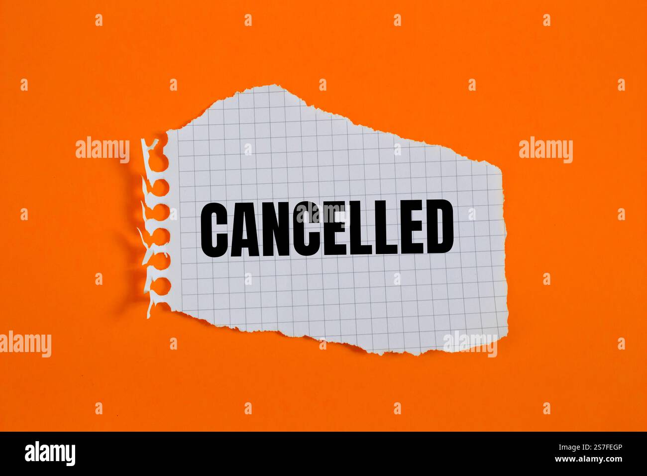 Cancelled message written on ripped torn checkered graph paper piece with orange background ...