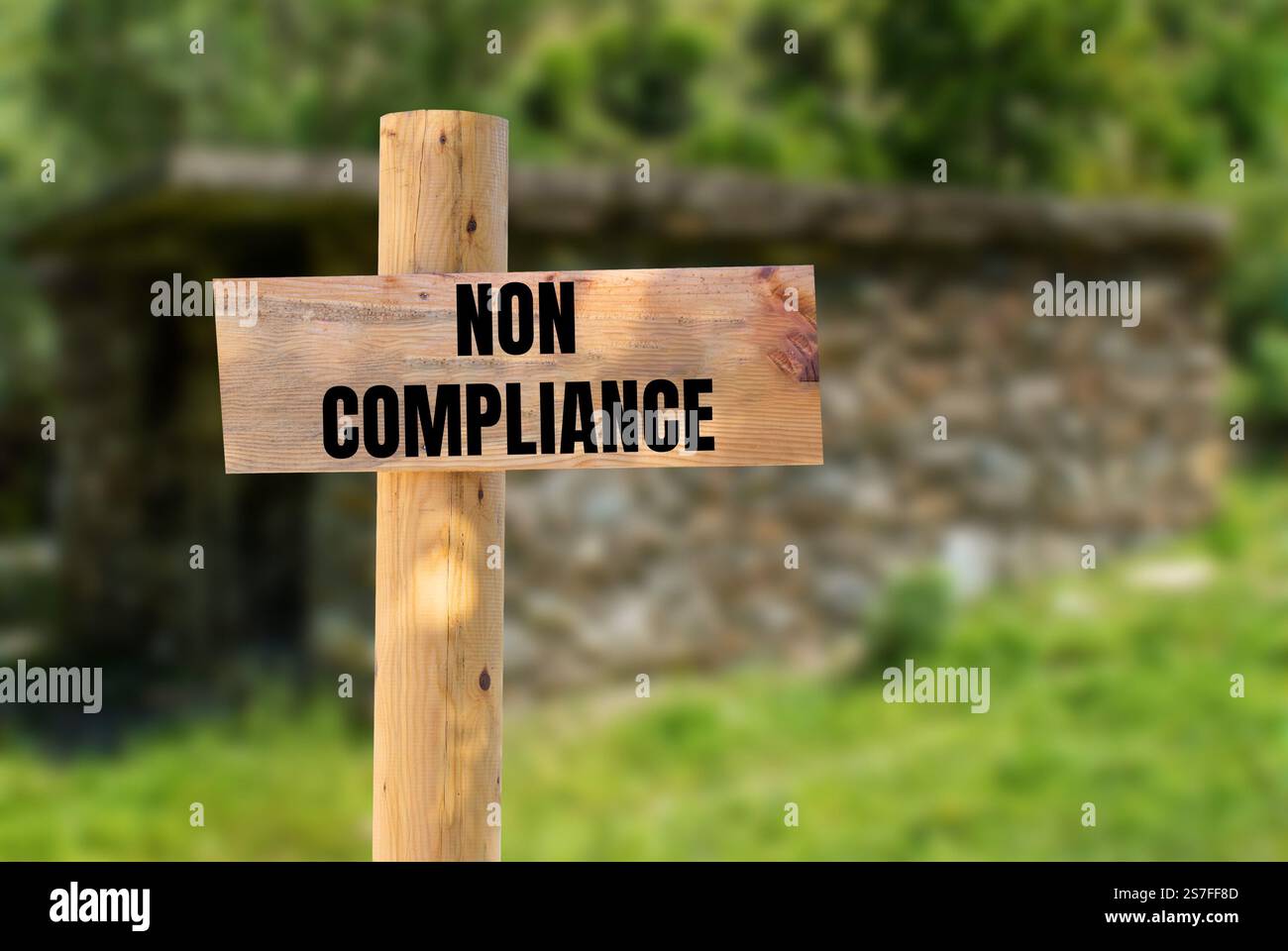 Non compliance message written on wooden sign with blurry nature ...