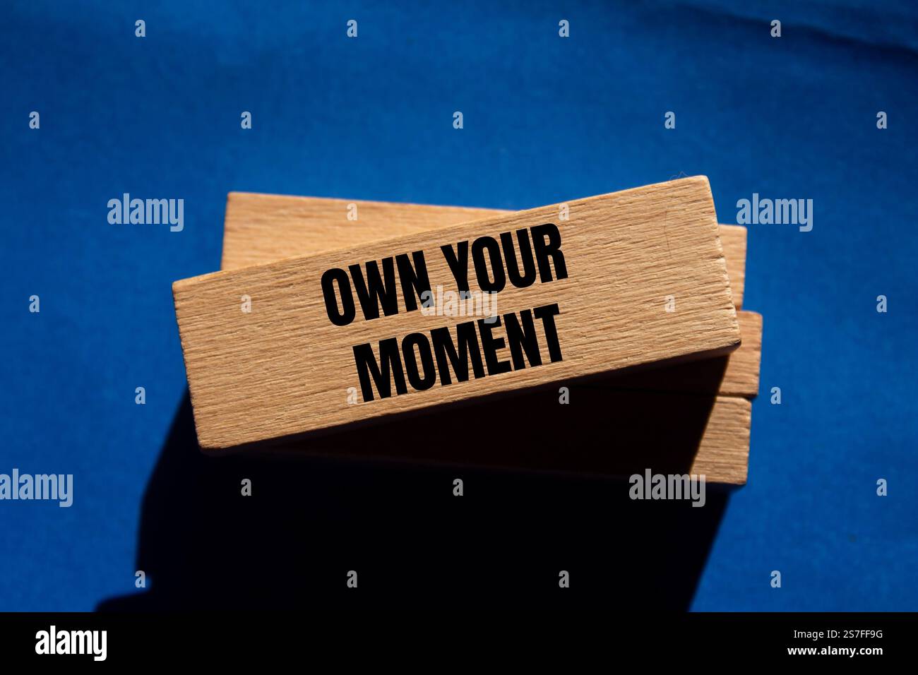 Own your moment message written on wooden blocks with blue background. Conceptual own your ...