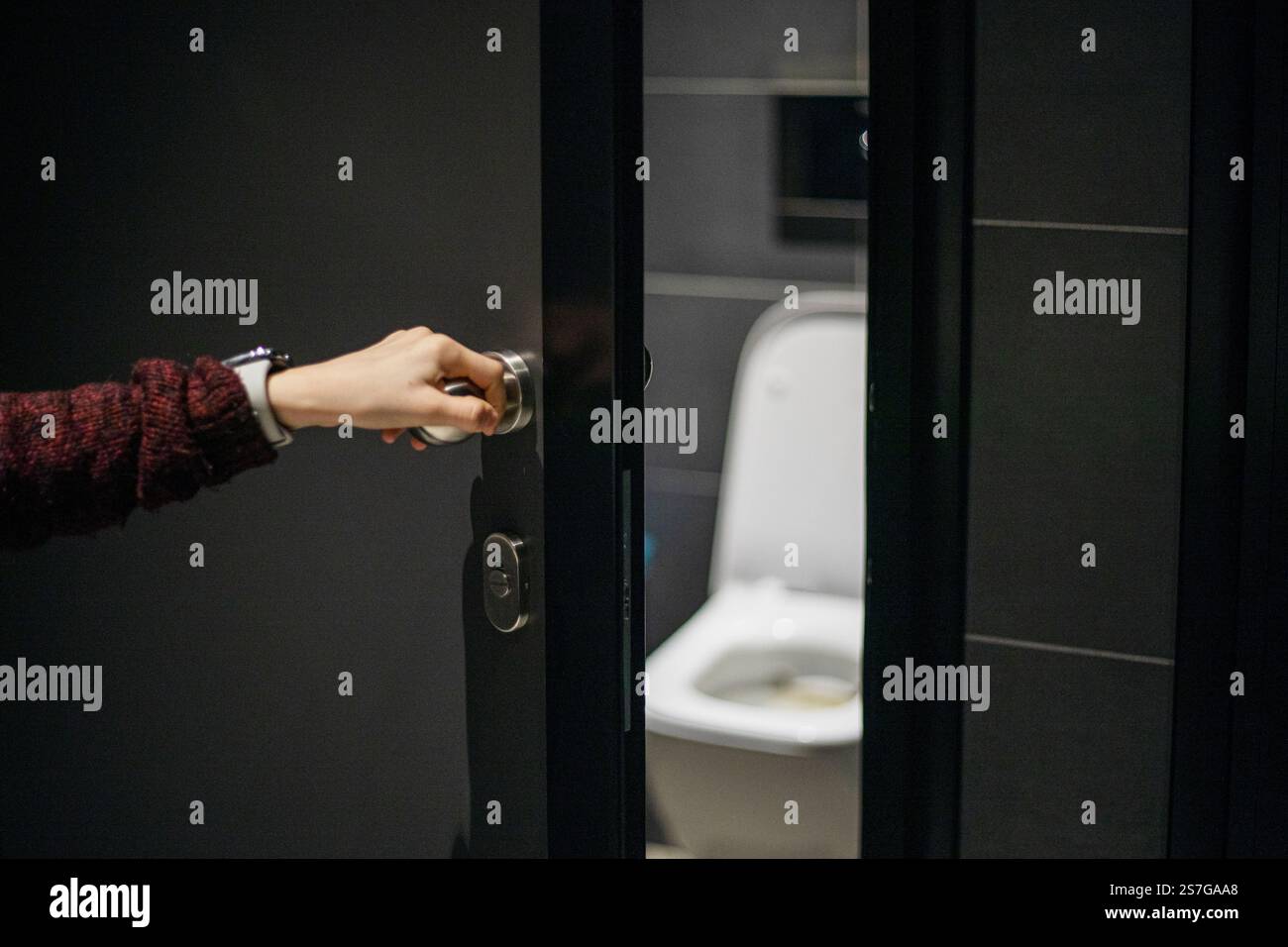 opening the door to the toilet room in a modern interior of dark colors ...