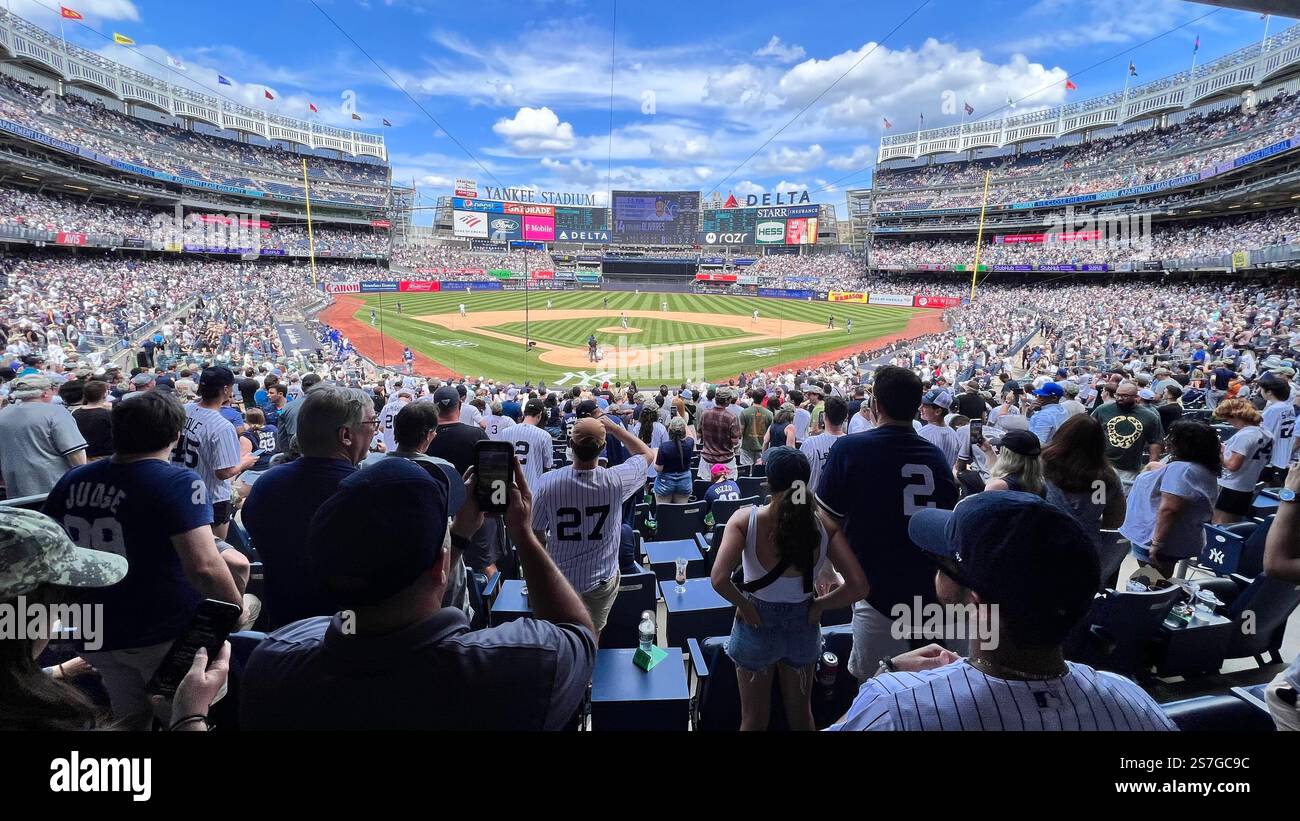 A vibrant crowd fills Yankee Stadium under a sunny blue sky, cheering on a thrilling baseball ...