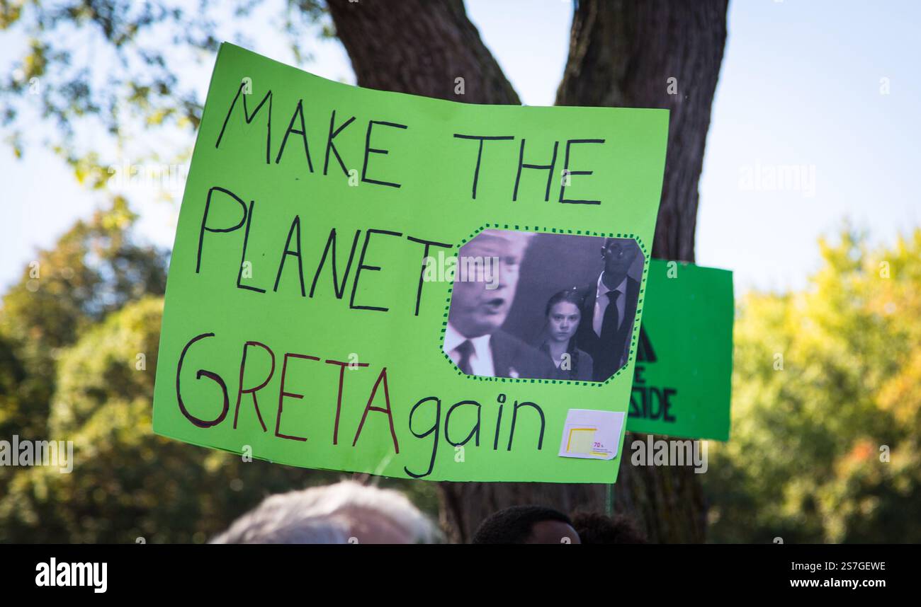 A green protest sign reading "Make the Planet Greta Again," featuring a ...