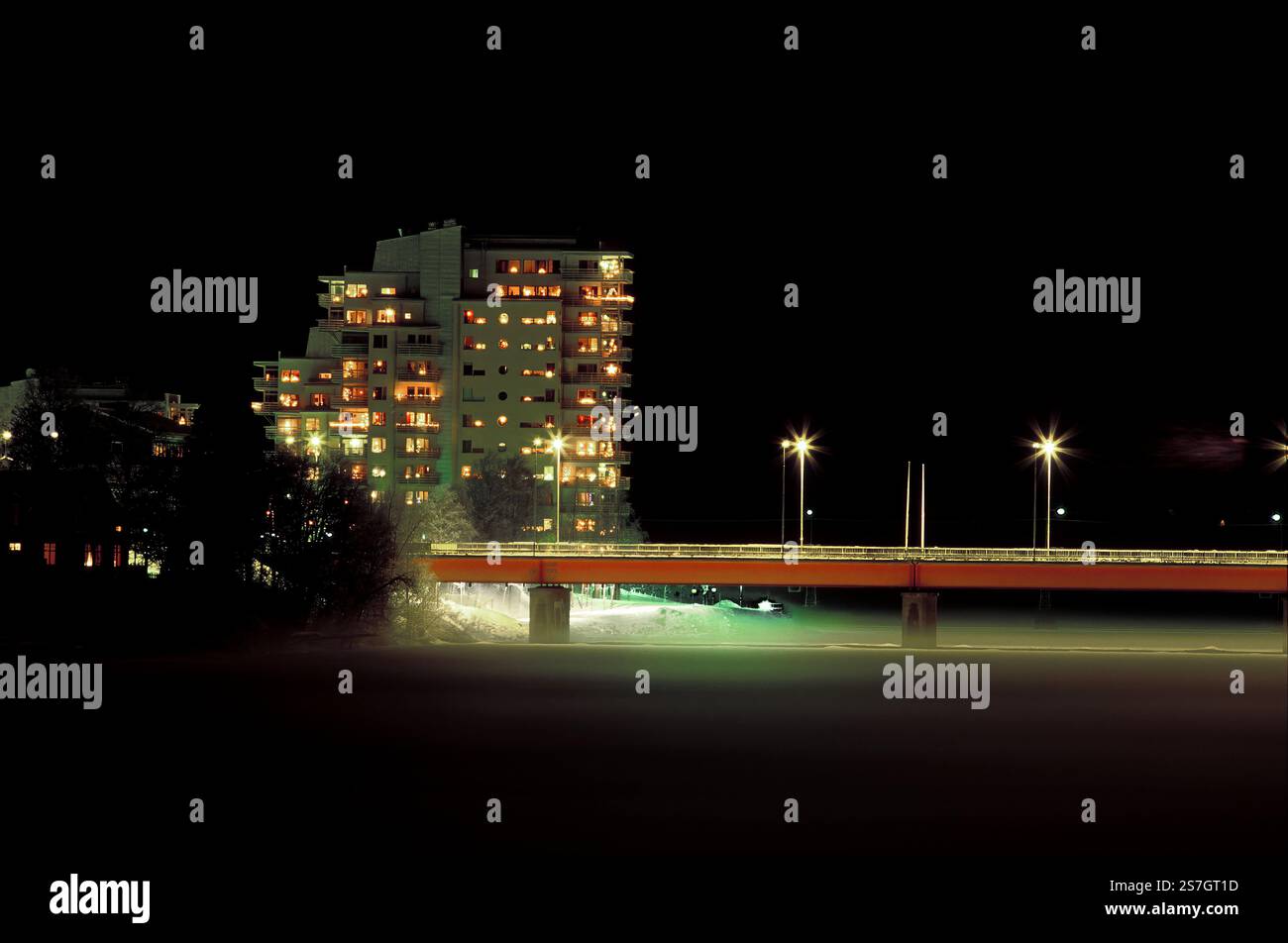 Night view of buildings, apartments, homes by a river. Lights in ...