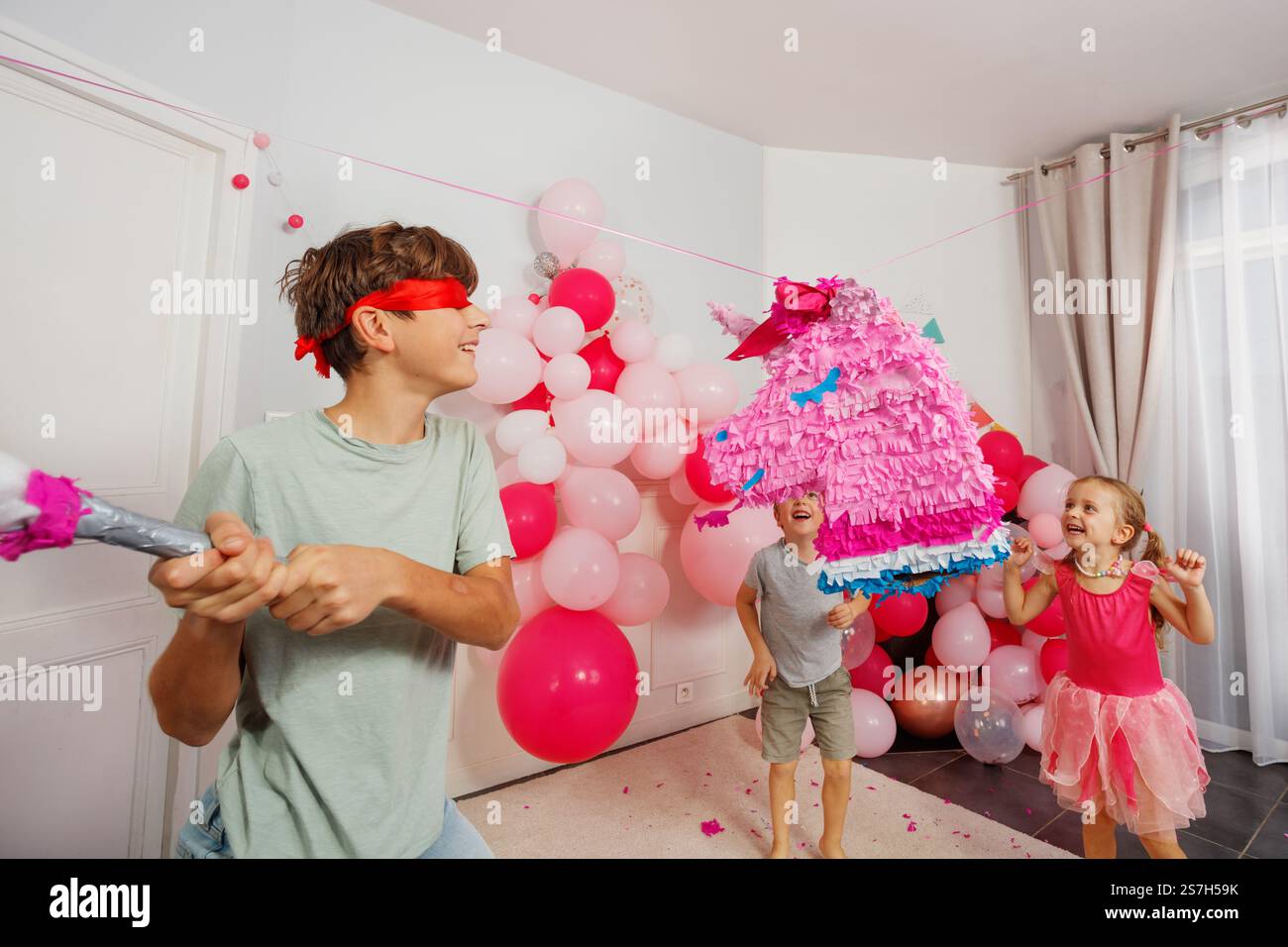 Surrounded by party decorations, a blindfolded child is about to strike ...
