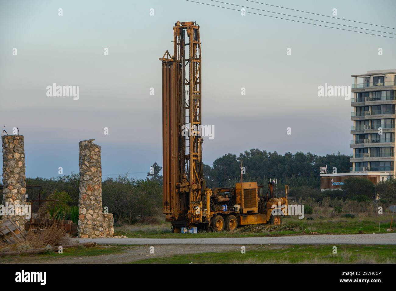 A towering drilling rig stands amidst a transitioning landscape under a ...