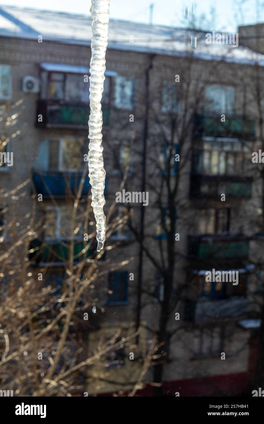 Icicle melting in sunshine outside building during early spring season ...