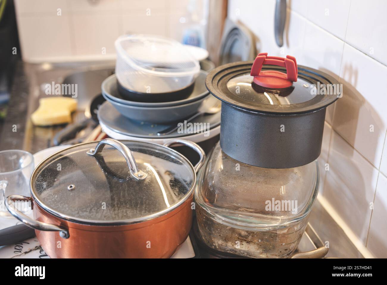 Stacked pots and dishes in a messy kitchen sink area during busy ...