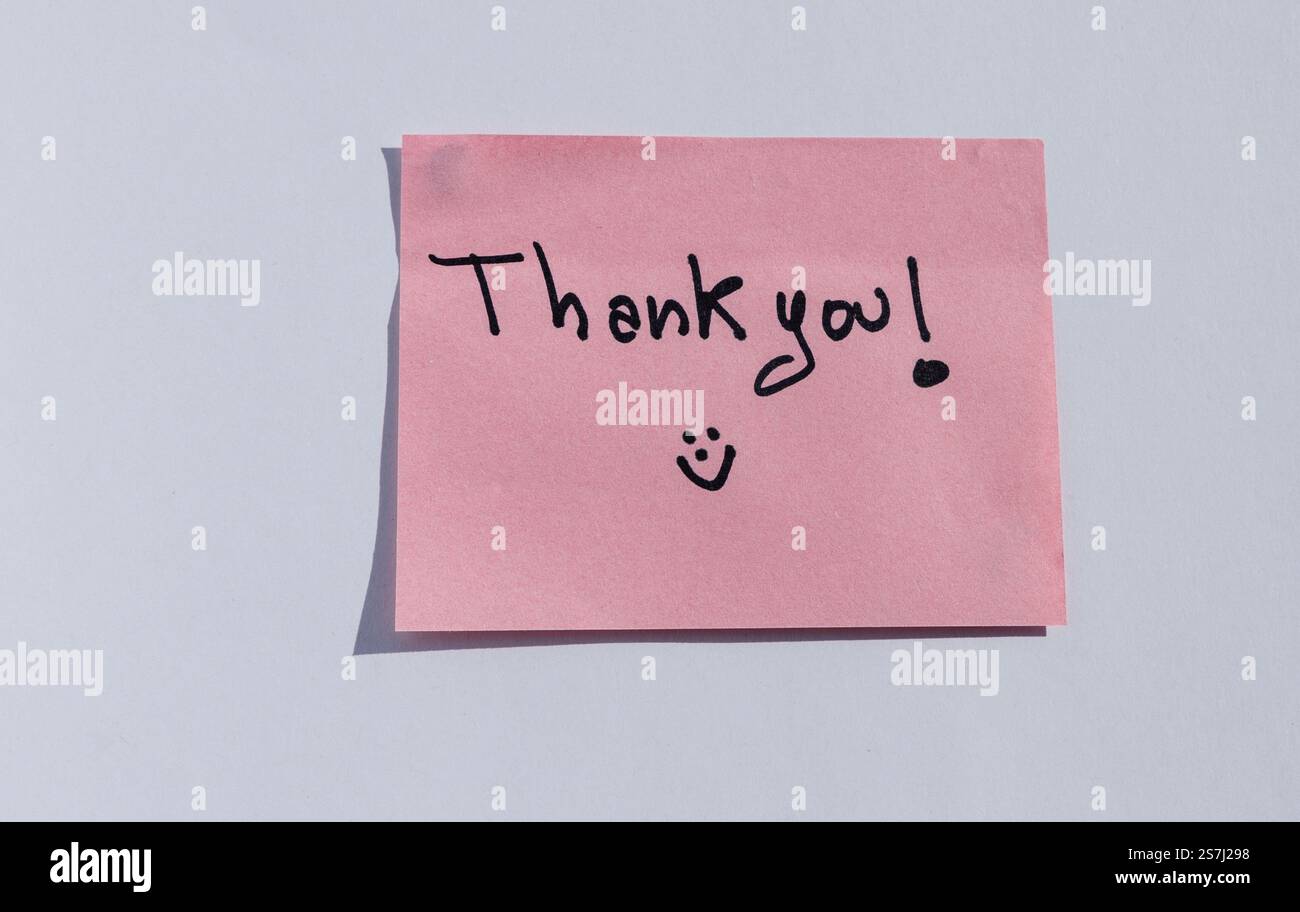 Handwritten 'Thank you!' message on a pink sticky note over a white ...