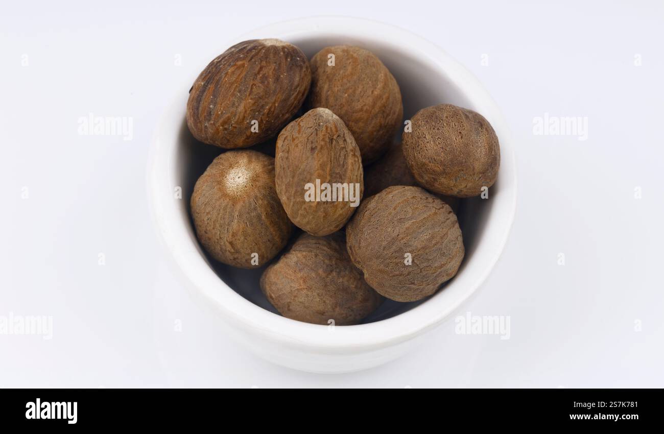 Nutmeg in a small bowl isolated on white background Stock Photo - Alamy