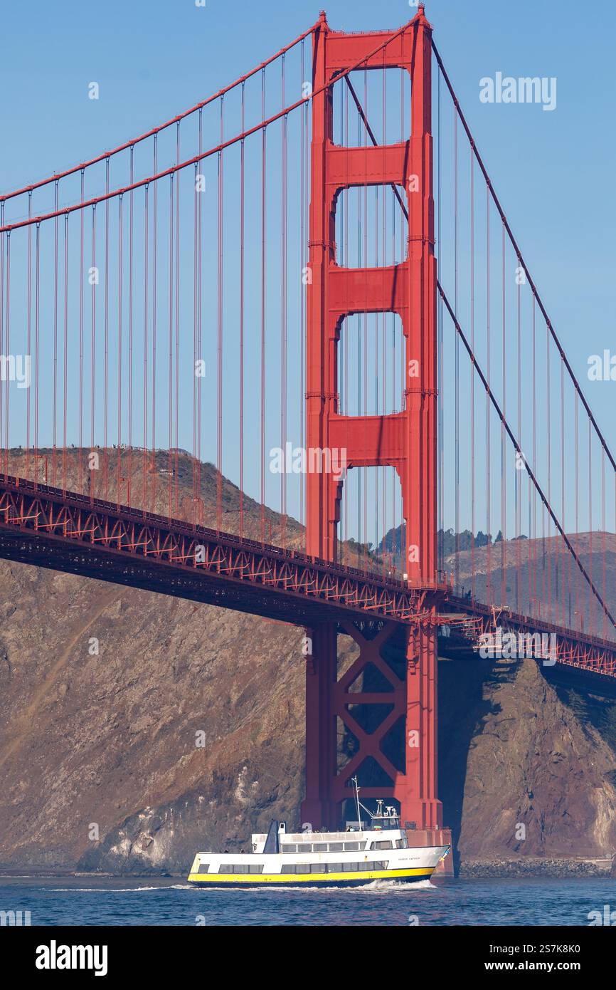 Ferry boat passes beneath the long and colorful span of Golden Gate ...