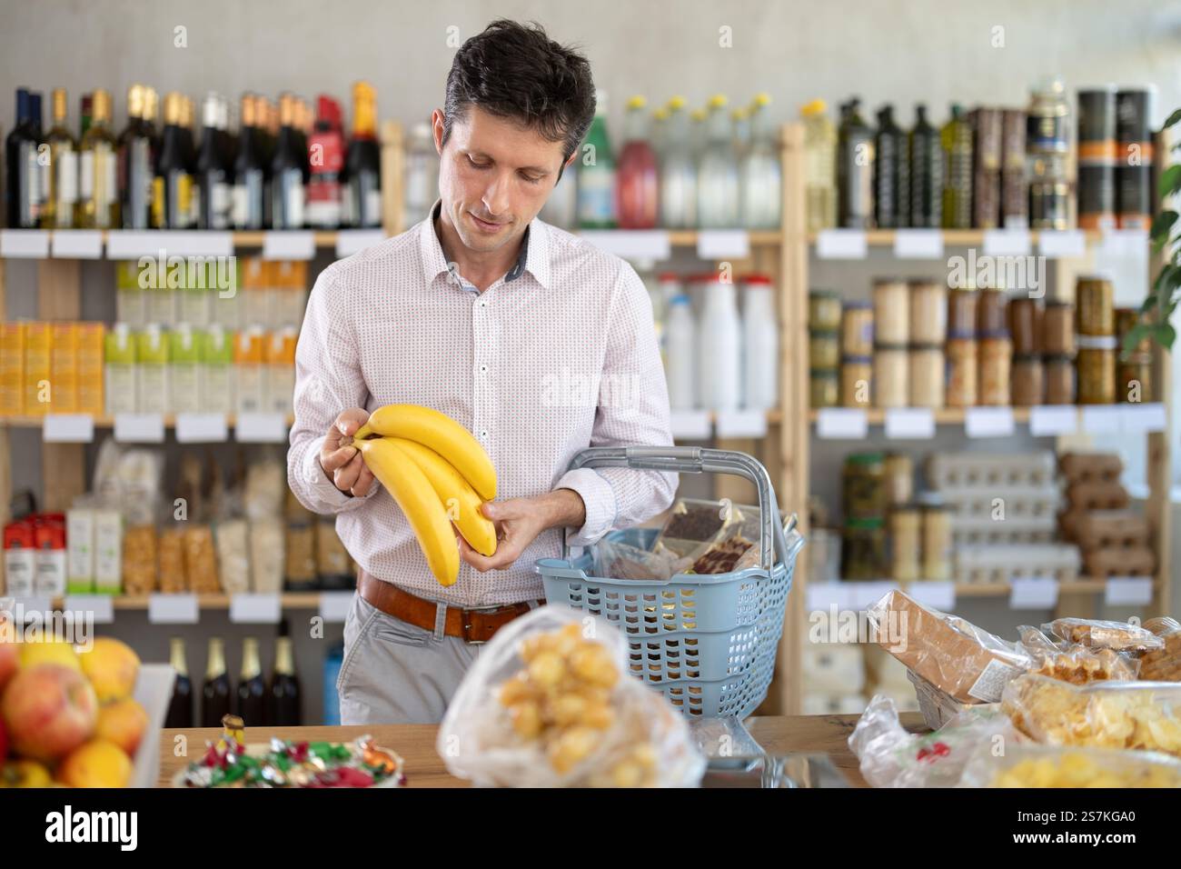 Near counter, man client takes out bananas from pile of fruits, chooses ...