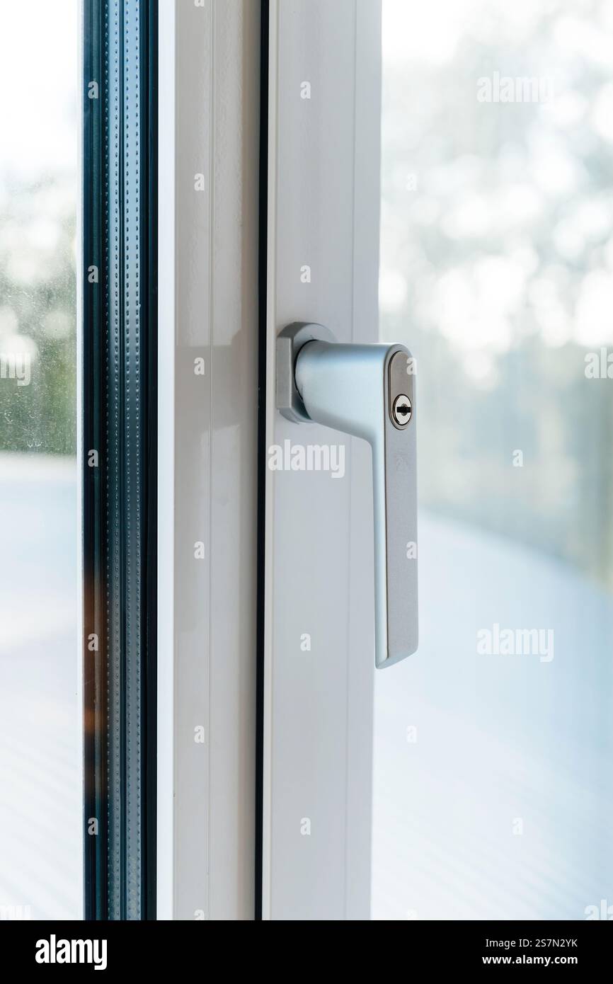 Sleek silver PVC window handle with a secure lock mechanism, framed by ...