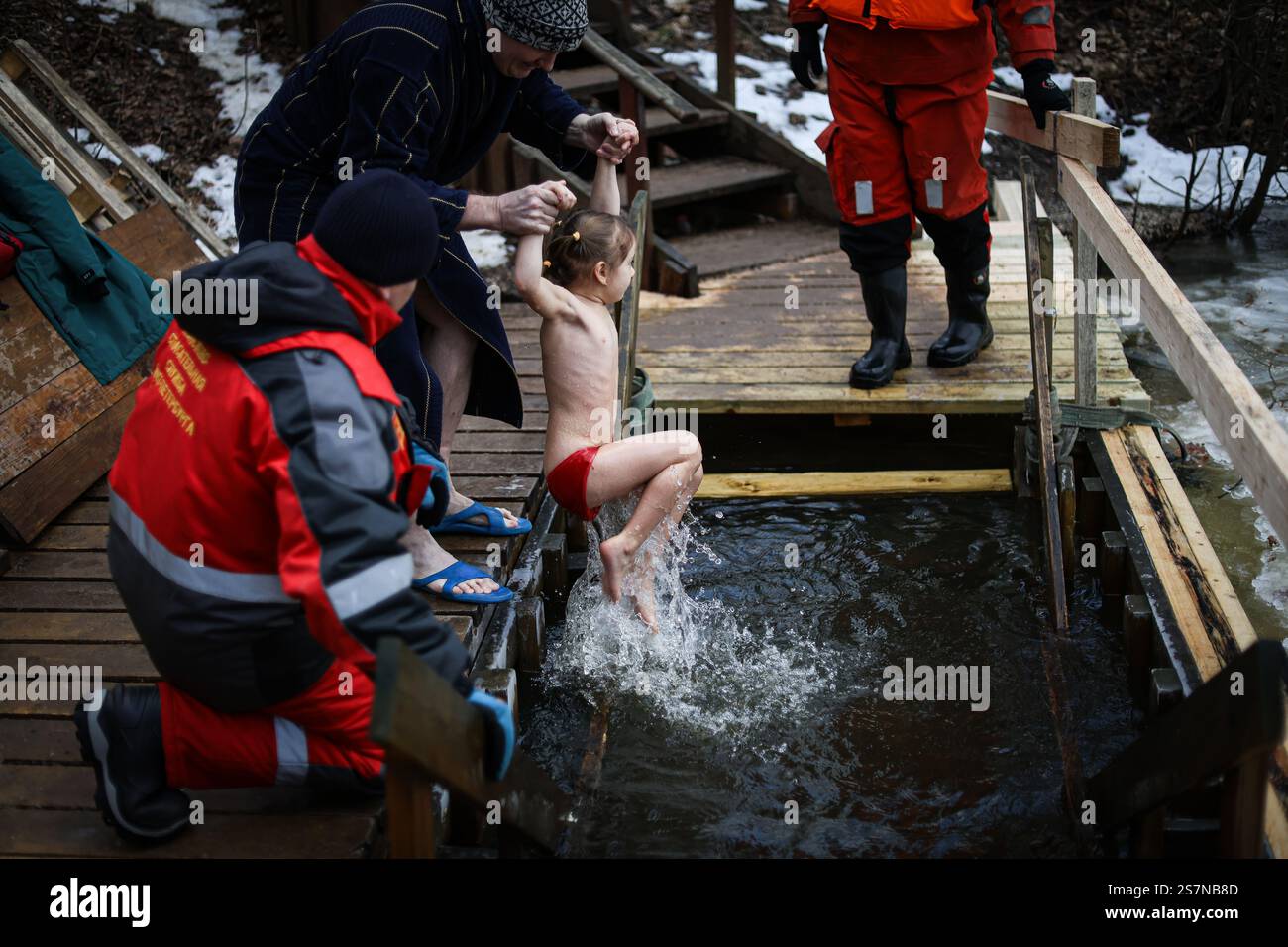 A man with his daughter seen during the Epiphany bathing in a font on ...