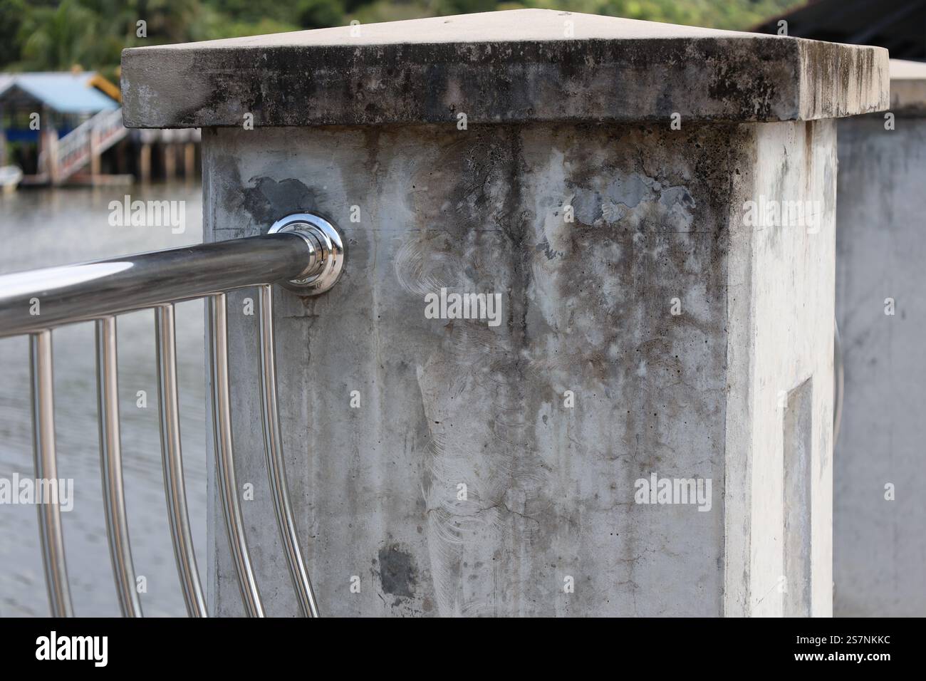 close-up concrete pillar supporting shiny chrome guard rails along a ...