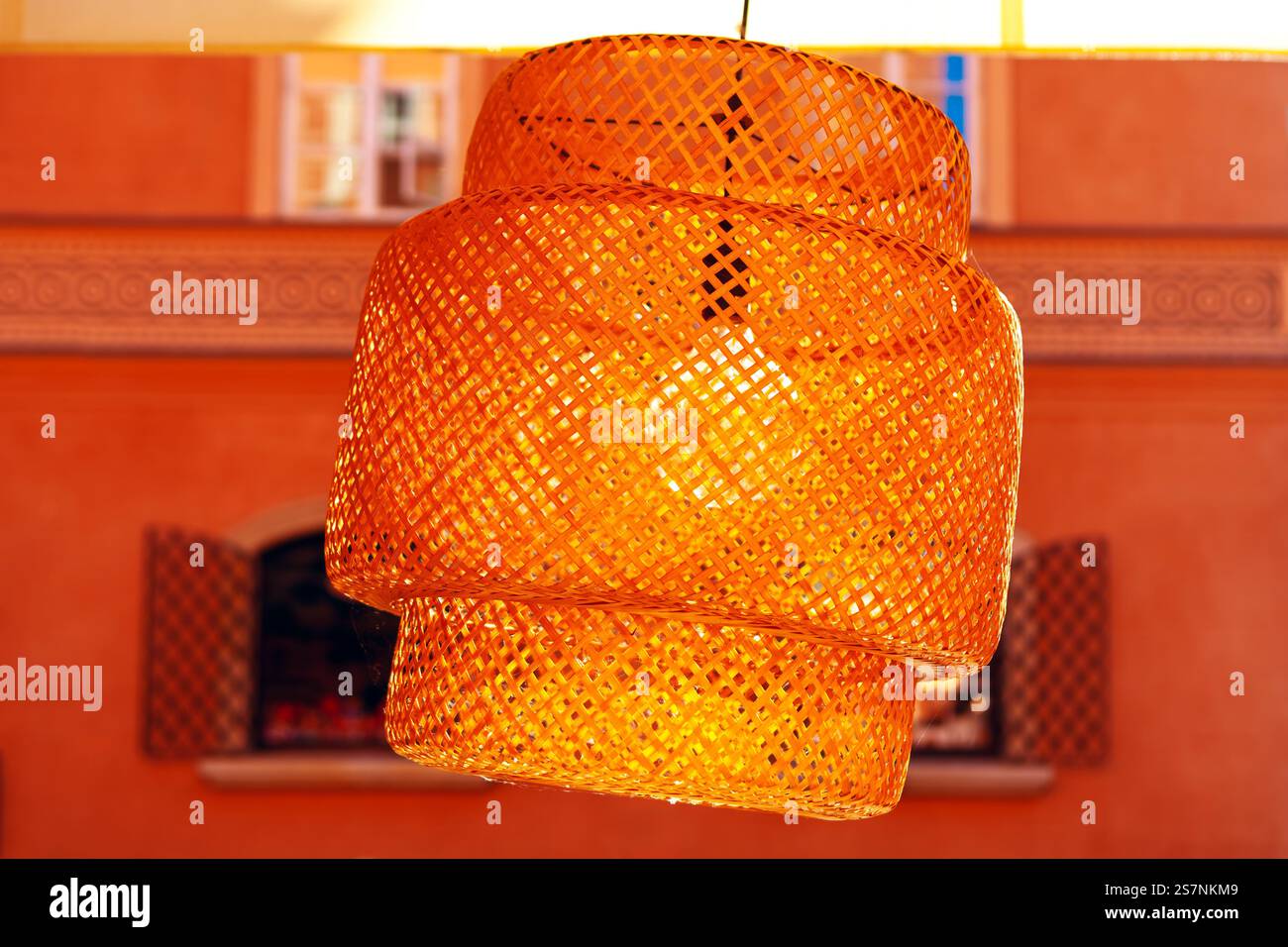 An intricate orange hanging lamp with a layered design takes center ...