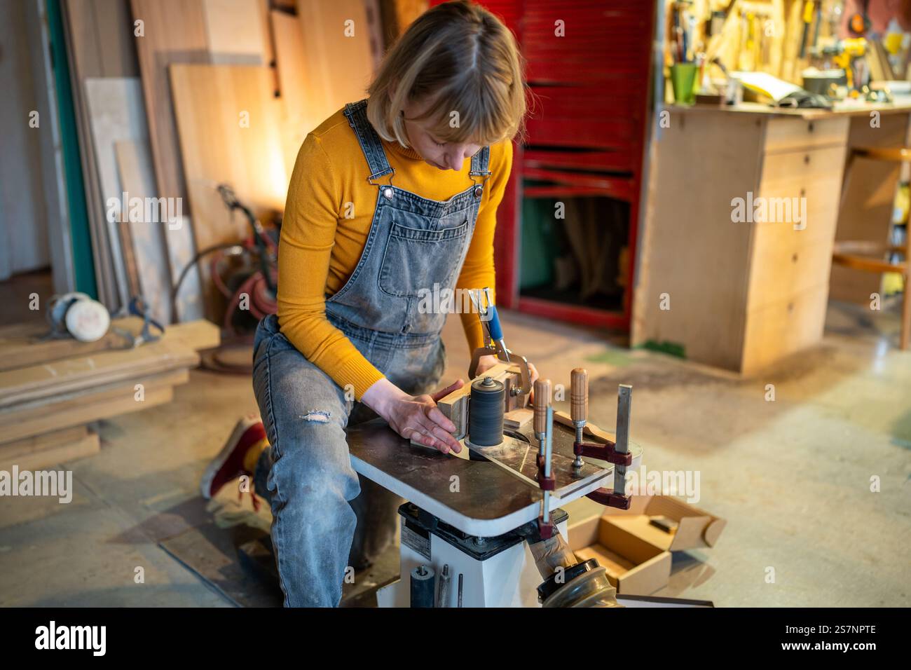 Pedant woman joiner works in joinery workshop, sanding, turning wooden ...