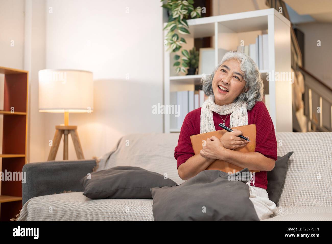 A happy Asian retired senior woman daydreams about her happiness while ...