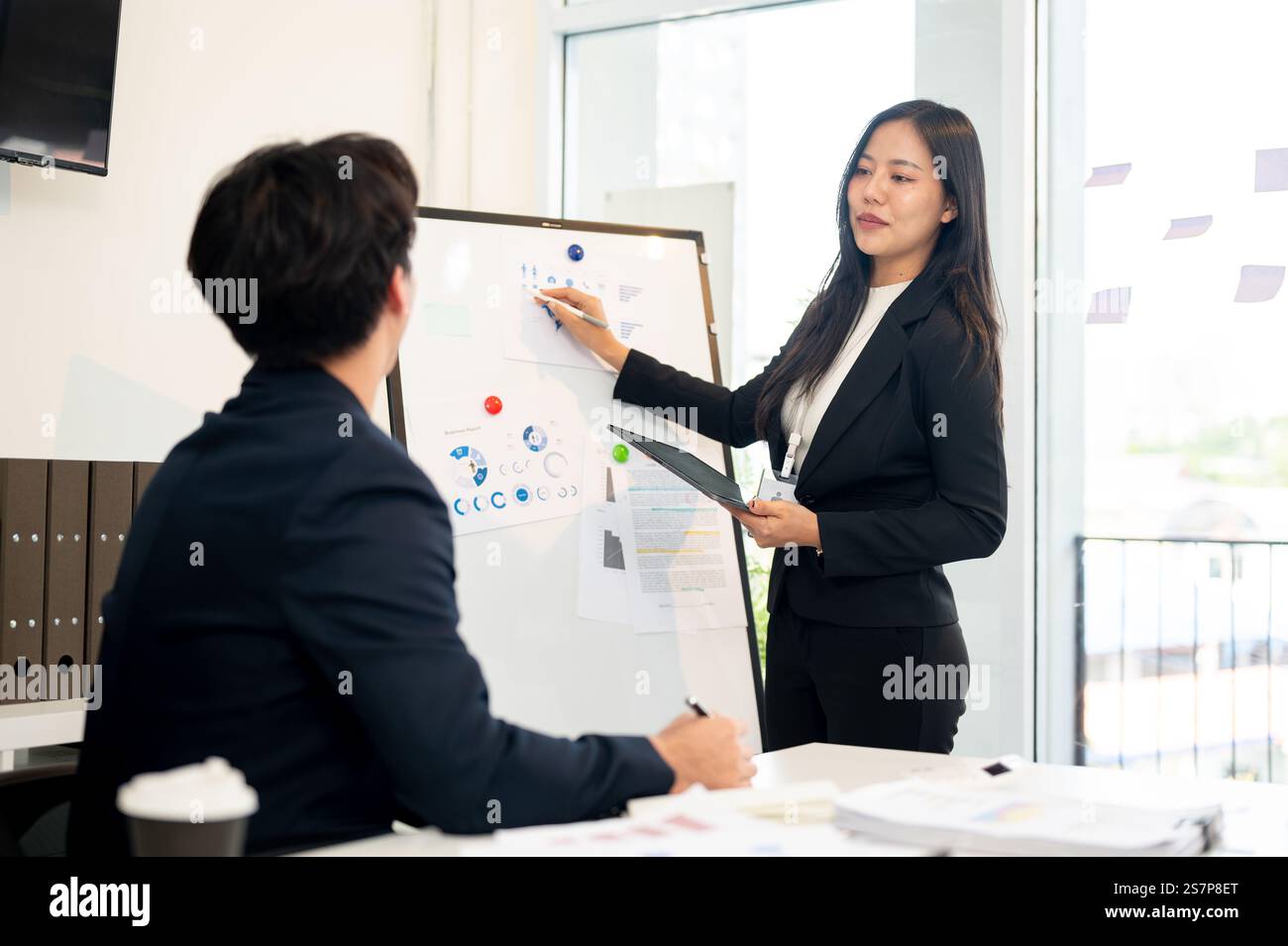 A confident, positive Asian businesswoman is presenting her project to ...