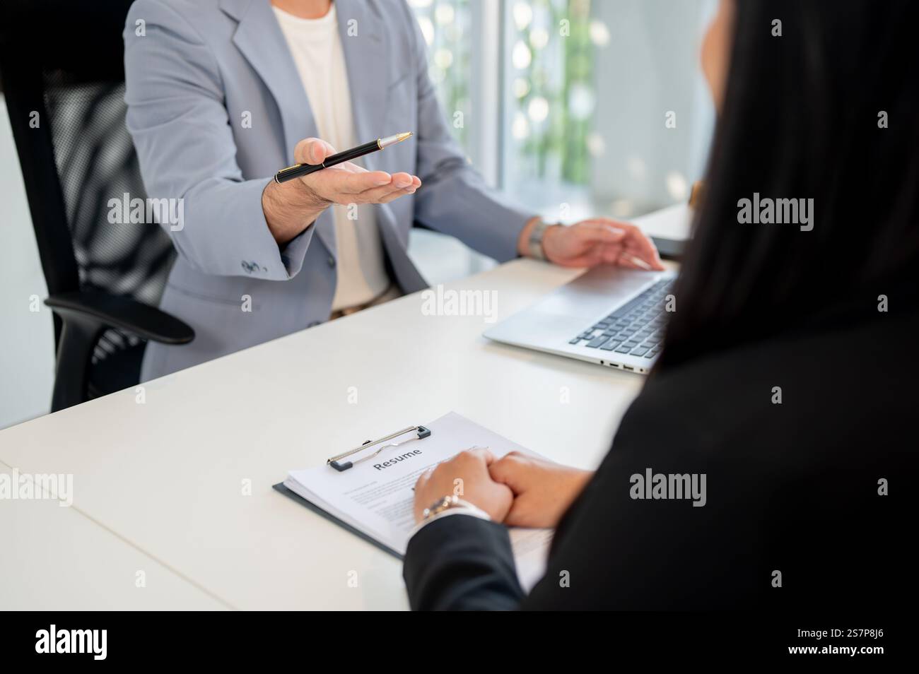 A close-up image of an Asian woman during a job interview with a male ...