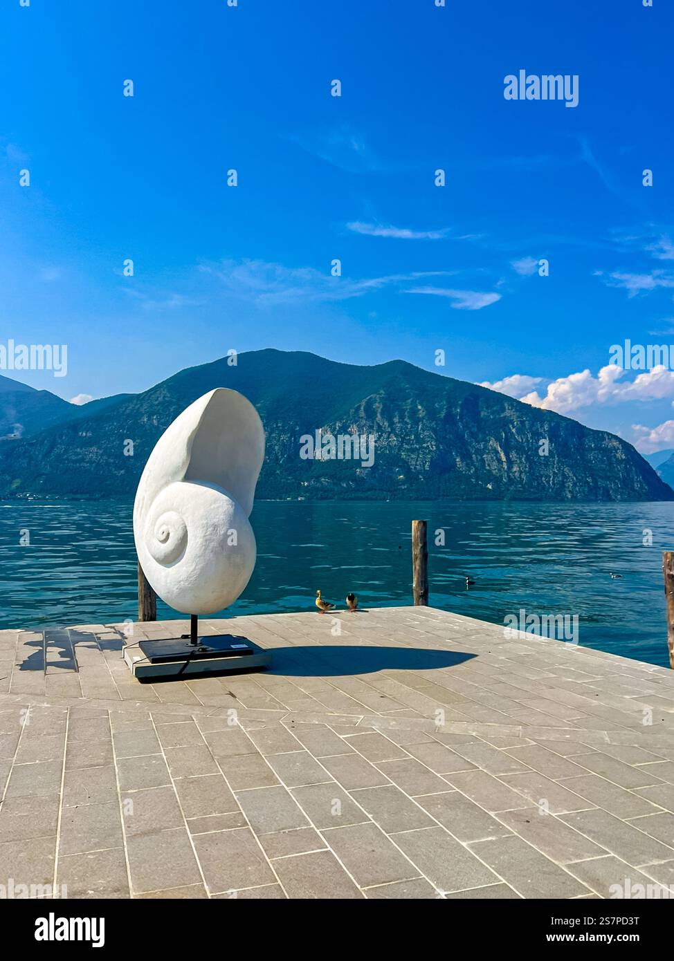 Abstract White Snail Shell Sculpture on a Stone Dock by a Calm Lake ...
