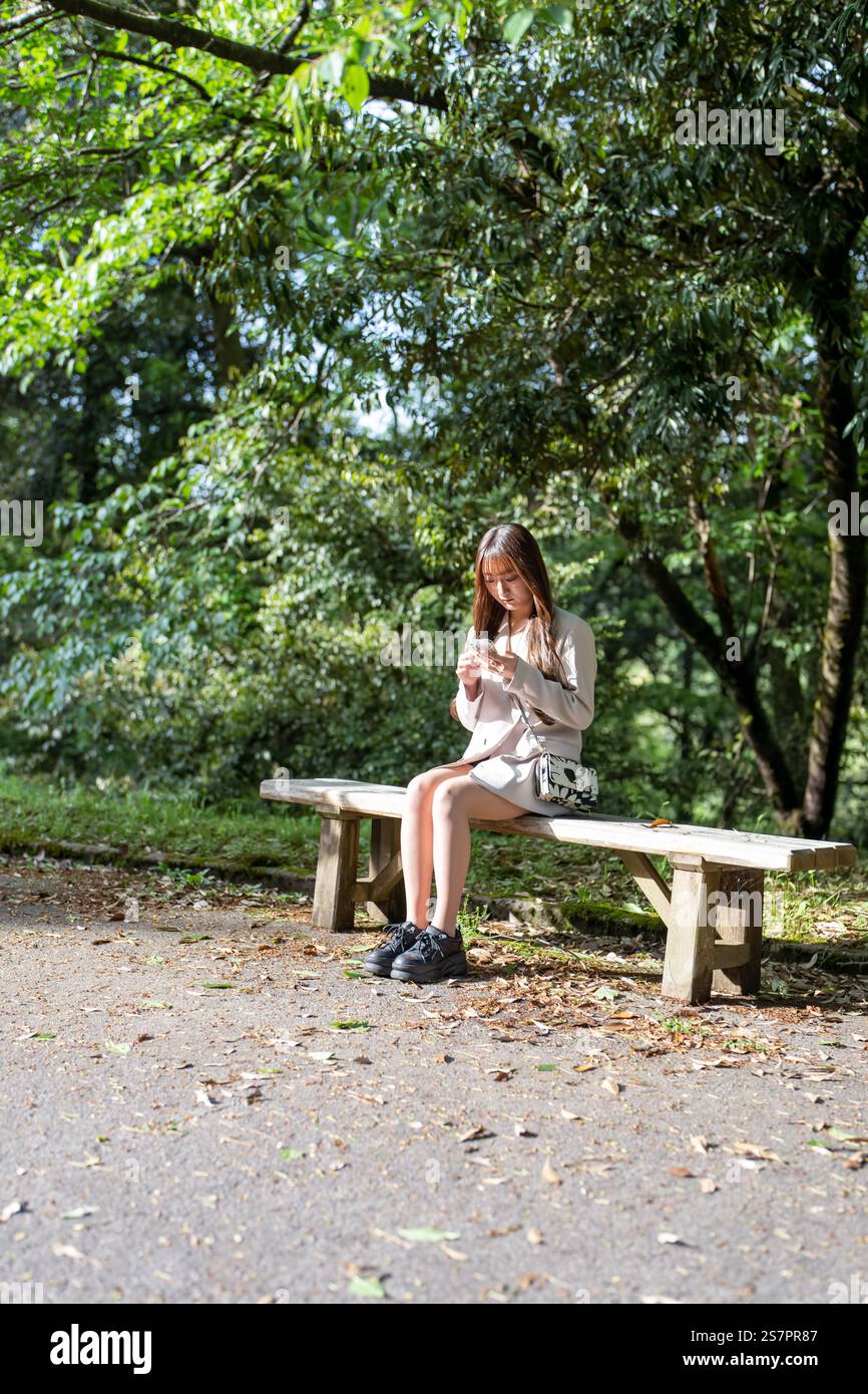 A Japanese woman in her 20s wearing white clothes sits at a desk in ...