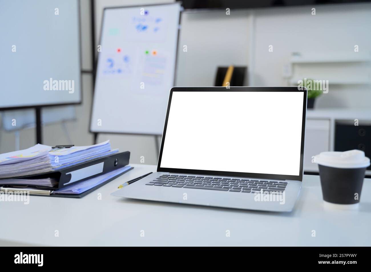 Laptop with empty screen, stack of folders, and a coffee cup in a ...