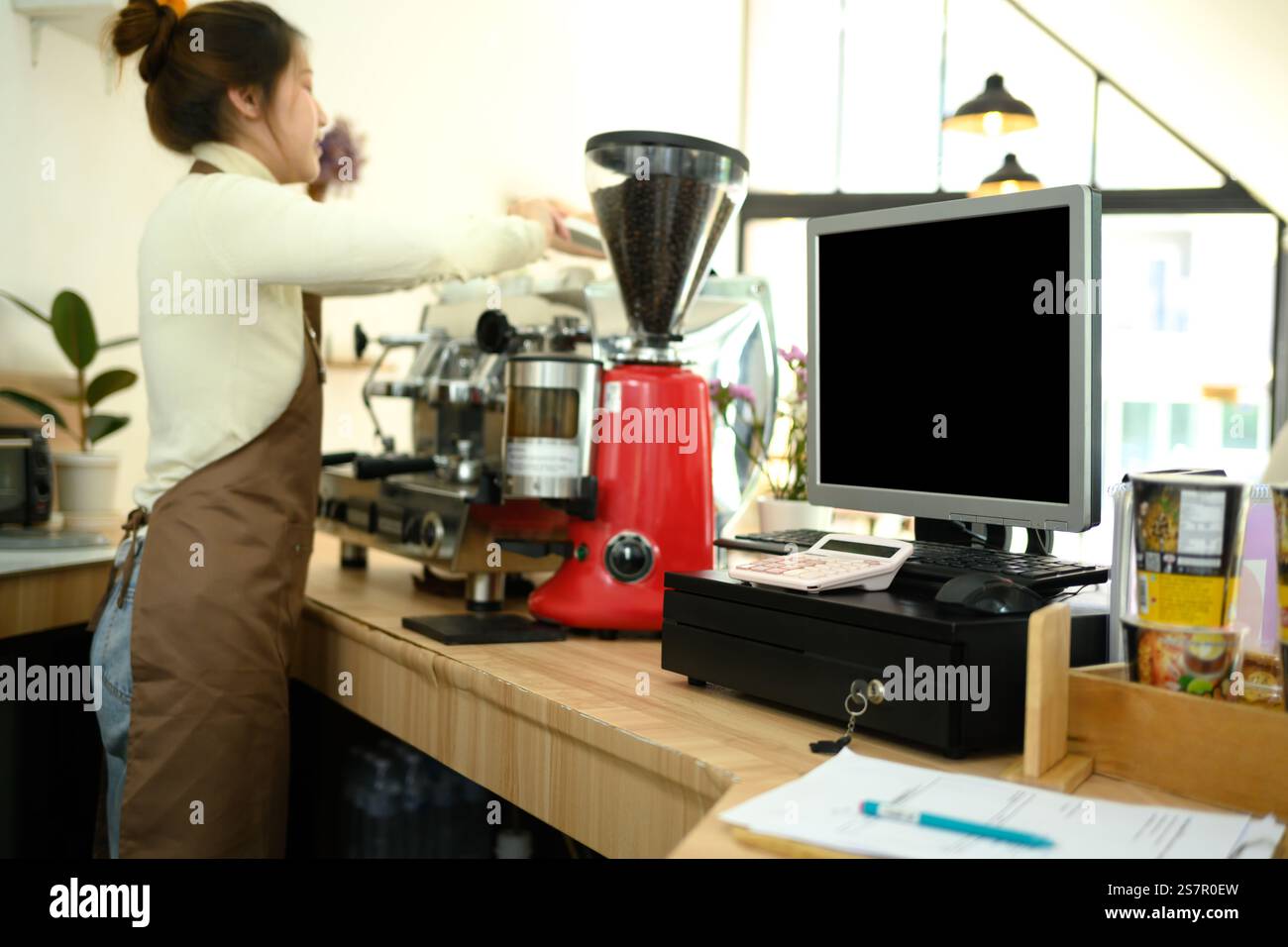Computer monitor and cash register on wooden counter with barista ...